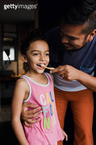 latin young single father teaching to his daughter how to brush teeth ...