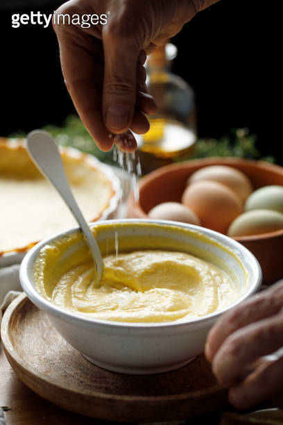 Preparing the filling for the tart, seasoning with salt the cheese and ...