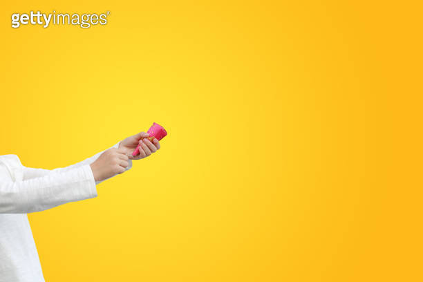 Close-up children hands shooting party popper confetti on empty yellow ...