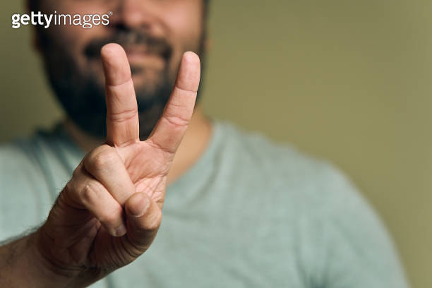 A bearded European man shows hand sign victory 이미지 (1648156516) - 게티이미지뱅크