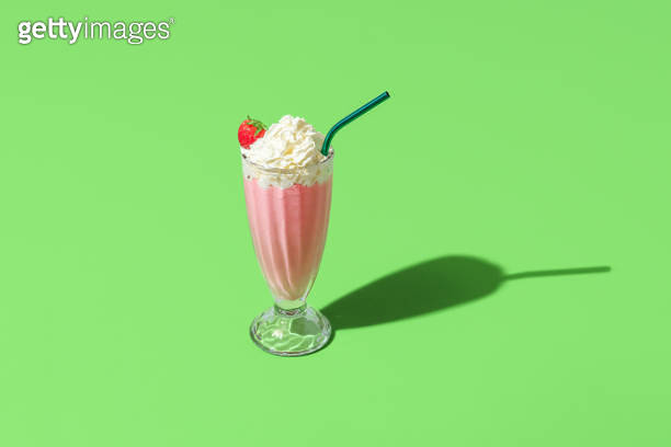 Milkshake glass minimalist on a green background. Homemade strawberries ...