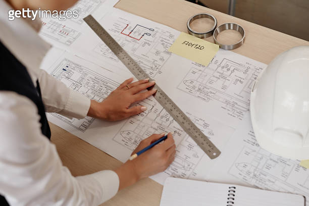 Female engineer drawing blueprints and plans at workstation in office ...