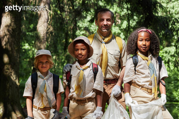 Group of scouts with adult leader looking at camera in forest 이미지 ...