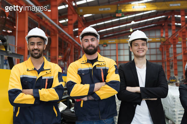Group of male factory workers standing together with crossed arms and ...