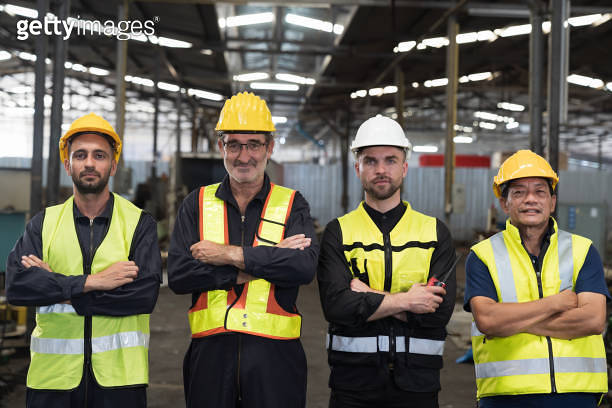Group of male factory workers standing together with crossed arms and ...