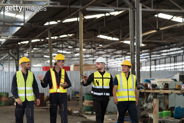 Group of male factory workers discussing of their work in industry ...
