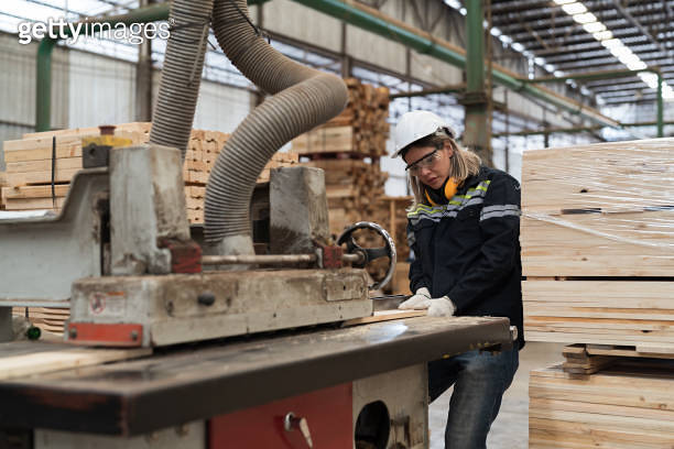 Female carpenter factory worker using wood rolling machine for process ...