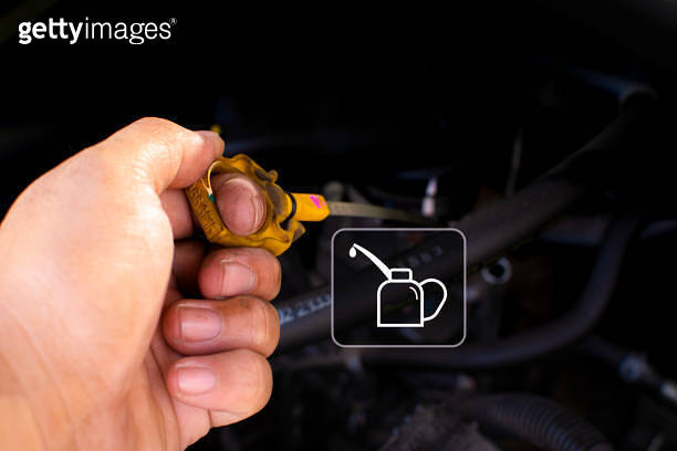 A mechanic check the car engine oil level by pulling the dipstick ...