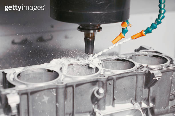 CNC milling machine grinds holes in car engine with coolant. Process of ...