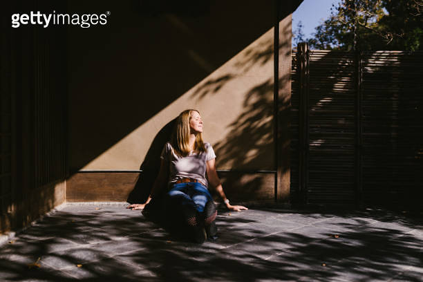 Woman sitting in sunshine with dappled light through trees 이미지 ...