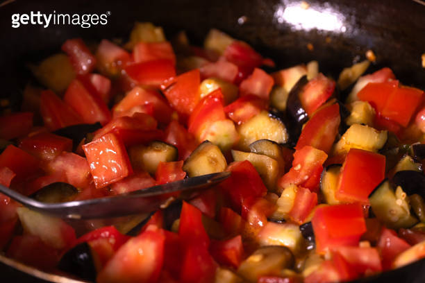 Close-up of tomatoes and eggplants fried in a frying pan. Mixing ...