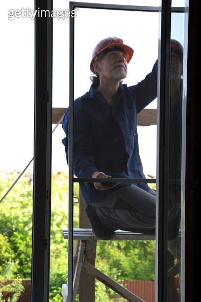 A worker on scaffolding in the window opening performs installation ...
