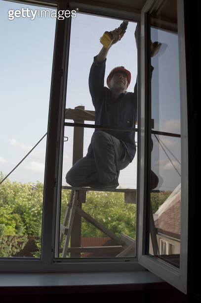 A worker on scaffolding in the window opening performs installation ...