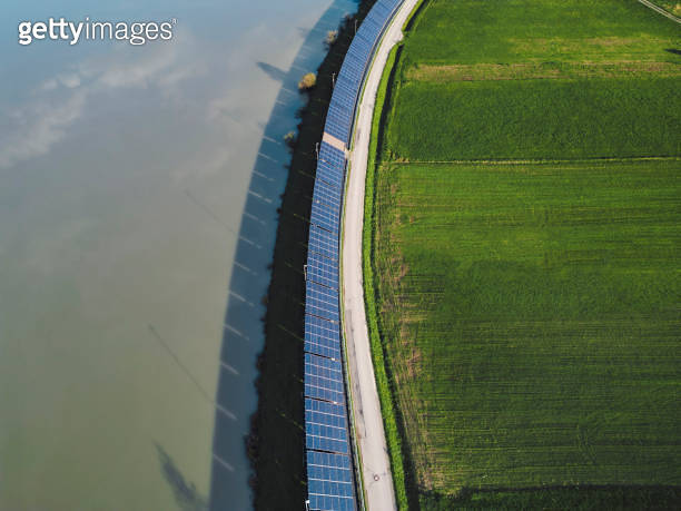 Line of solar panels farm near river. Rows of sustainable energy solar ...