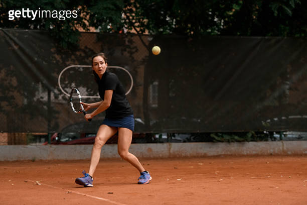 female tennis player with racket ready to hit tennis ball flying ...