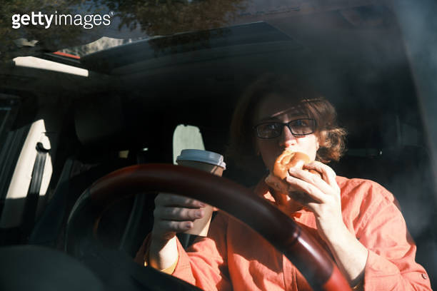 45-year-old woman eating sweat bread and drinking coffee from paper cup ...