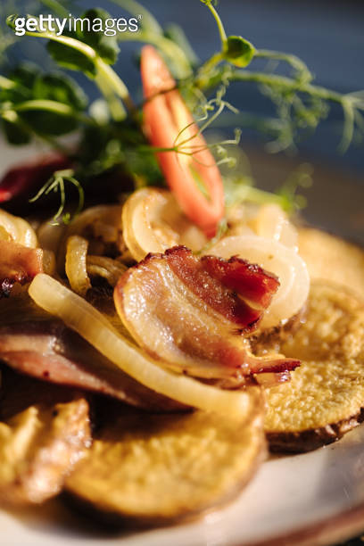 Macro photo of fried ring potatoes with bacon in a plate outdoor ...