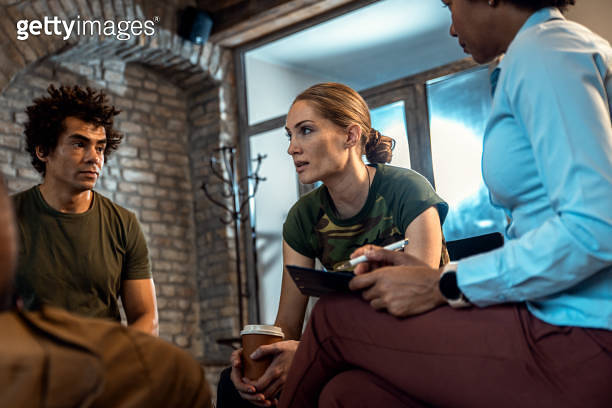 Female soldier talking with diverse group of veterans during PTSD ...