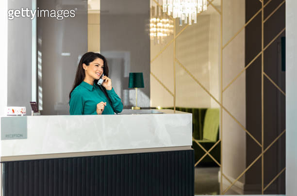 Portrait of female receptionist working at reception desk in hotel ...