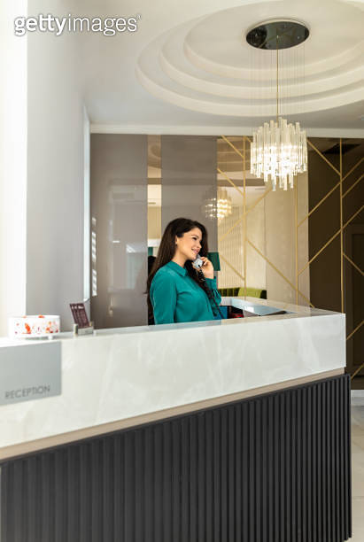 Portrait of female receptionist working at reception desk in hotel ...