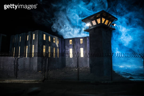 Old prison watchtower protected by wire of prison fence at night ...