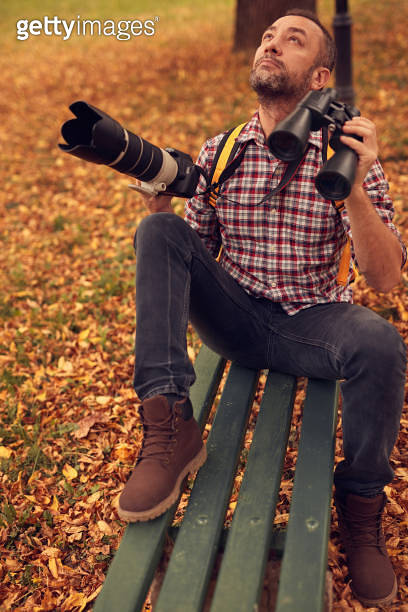 Man using binoculars and camera for bird and animal watching in nature ...