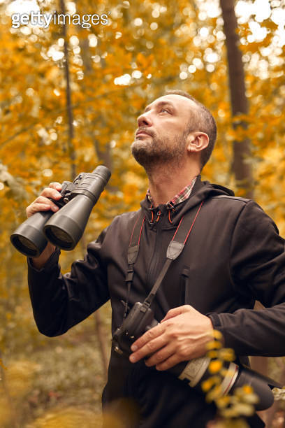 Man using binoculars and camera for birdwatching and other observing ...