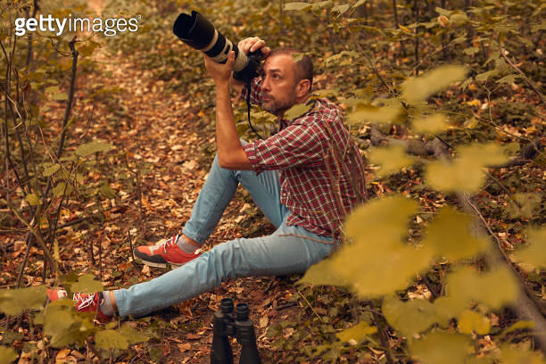 Man using binoculars and camera for birdwatching and other observing ...