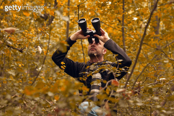 Man using binoculars and camera for birdwatching and other observing ...