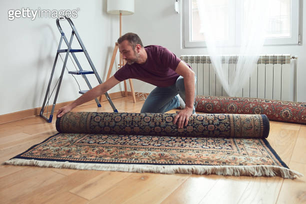 Man rolling rugs in the apartment. (1846844749) - 게티이미지뱅크