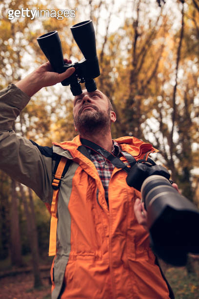 Man using binoculars and camera for bird and animal watching in nature ...