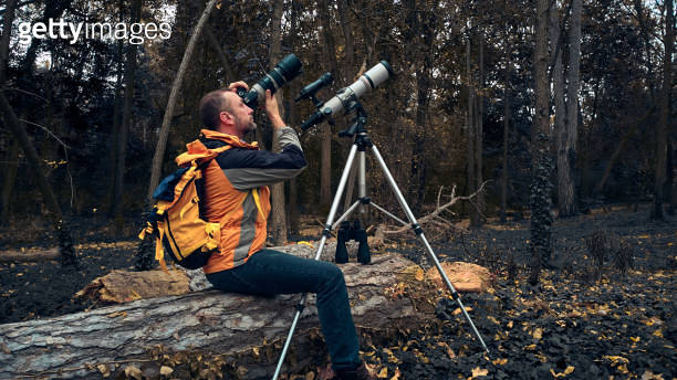 Man using telescope and camera for bird and animal watching in nature ...