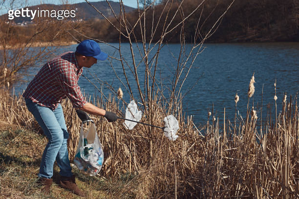 Volunteer and environmental activist cleaning dirty lake shore filled ...