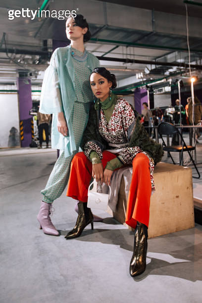 Group female portrait of two fashion models indoors. Behind the scenes ...