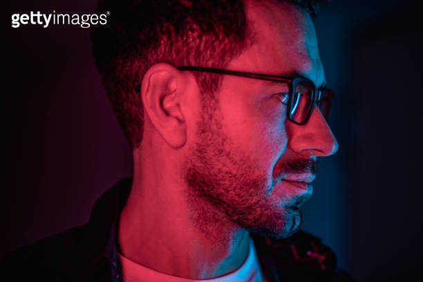 Male portrait of man with neon lighting. Red, blue, purple and magenta ...