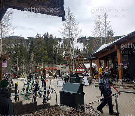 People with skis walking through the village plaza at the base of ...