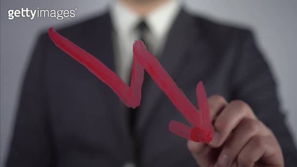 Businessman draws a graph of negative market growth. A man in a suit ...