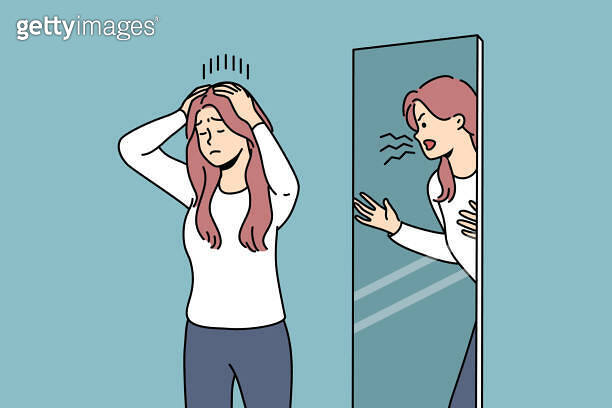 Woman is trying to restrain aggression, standing near mirror with angry ...