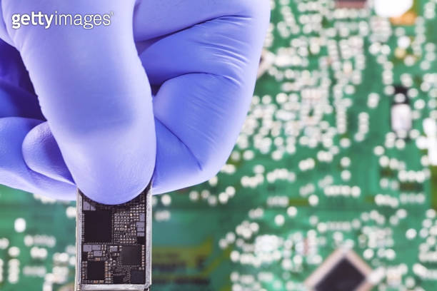 Blue gloved hand showing an electronic component on an integrated ...