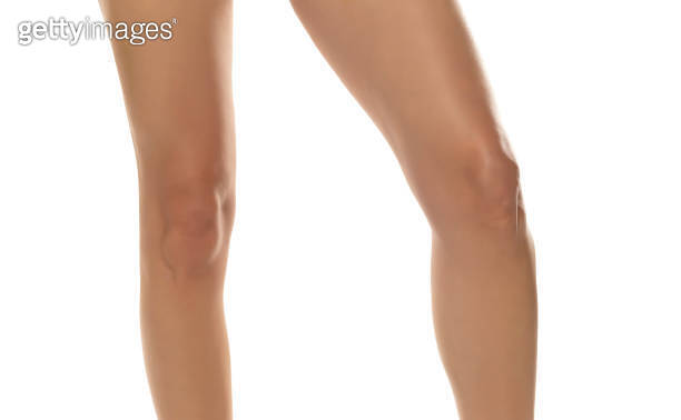 Female knees in a standing pose on white background. This composition ...