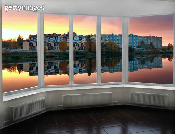 Panoramic window with view of red sunset above city buildings. Evening ...