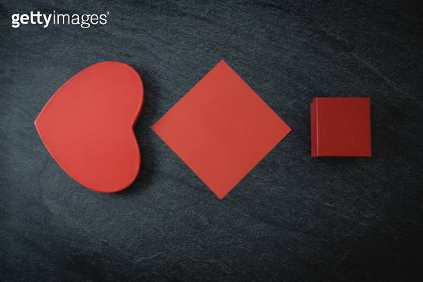 Two red heart boxes and an empty sheet on a black stone background ...