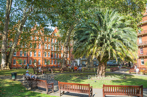 Local park in Mayfair with beautiful periodic buildings around. People ...