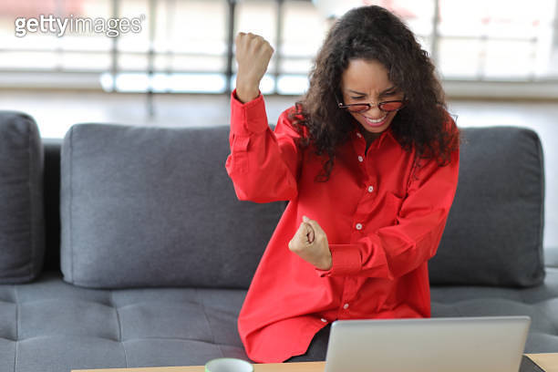 Happy woman sitting and using computer and raising hands with happy ...