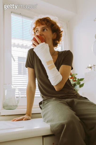 teenage girl with broken arm in cast in kitchen sitting on countertop ...