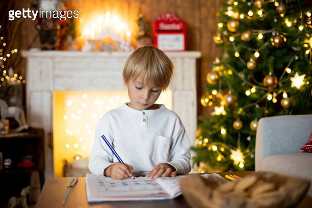 Beautiful blond child, young school boy, writing homework for school in ...