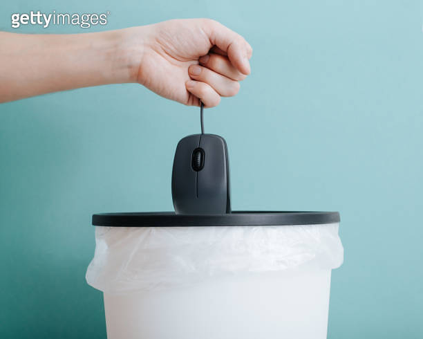 Close-up of hand throwing wired computer mouse into trash can, outdated ...
