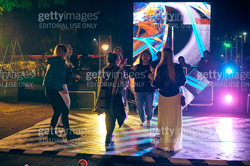 Funny people night dancing at outdoor dance floor with multicolored ...