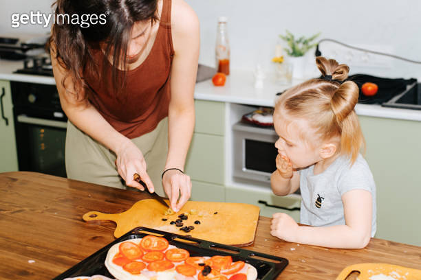 Family culinary food hobby, little cute caucasian girl eating toppings ...