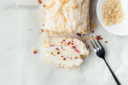 Cut of homemade meringue roll decorated with almond flakes and freeze ...